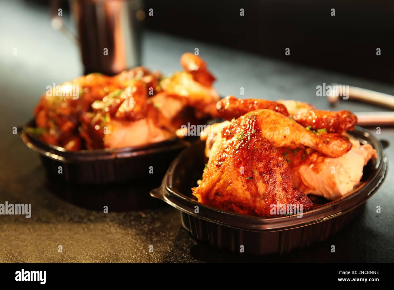 Cooked pieces of grilled chicken in plastic containers on bar counter ...