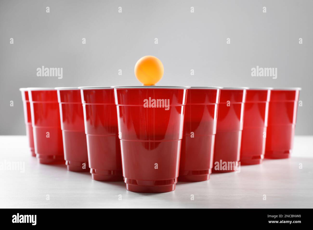 Plastic cups and ball for beer pong on white table Stock Photo - Alamy