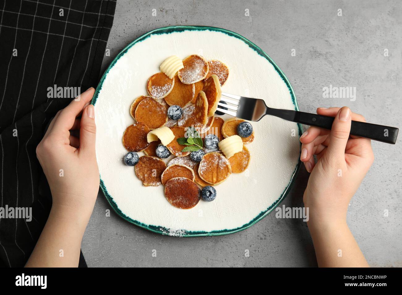 Woman eating cereal pancakes at light grey table, top view Stock Photo ...