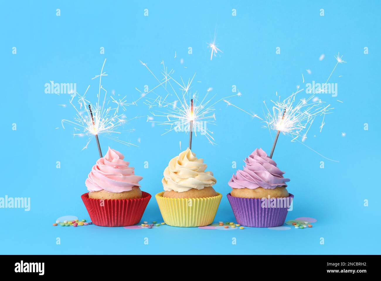 Birthday cupcakes with burning sparklers and sprinkles on light blue background Stock Photo - Alamy