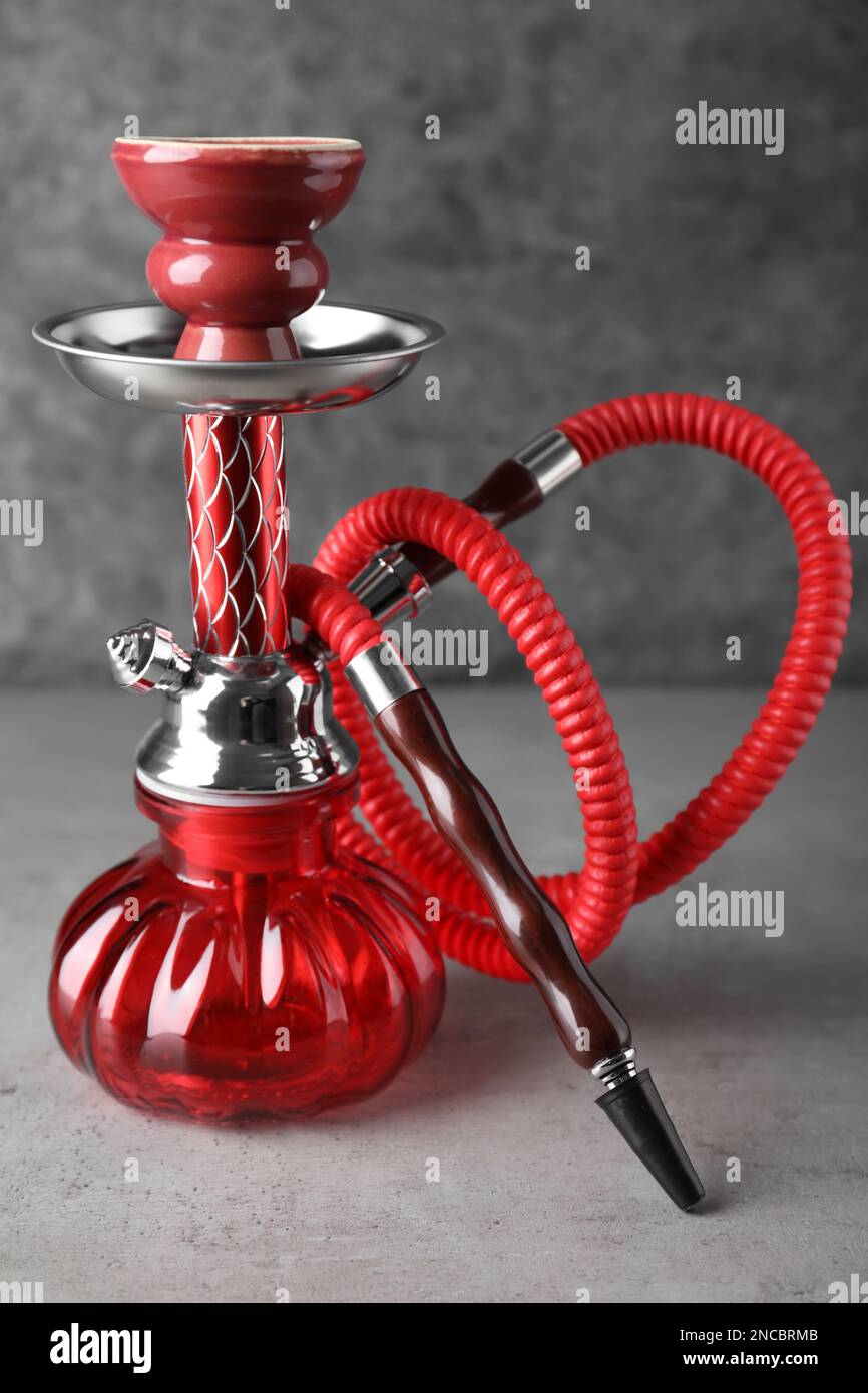 Modern red hookah on table against grey background Stock Photo - Alamy