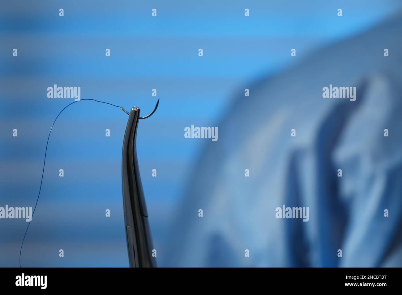 Forceps with suture thread on blurred background, closeup. Medical ...