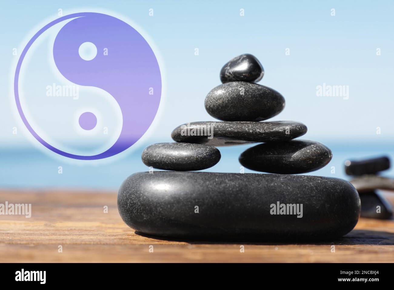 Stack of stones on wooden table outdoors and Ying Yang symbol. Feng ...