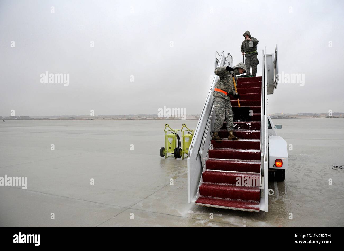 Two Air Force sergeants shovel snow and ice from the staircase truck in ...
