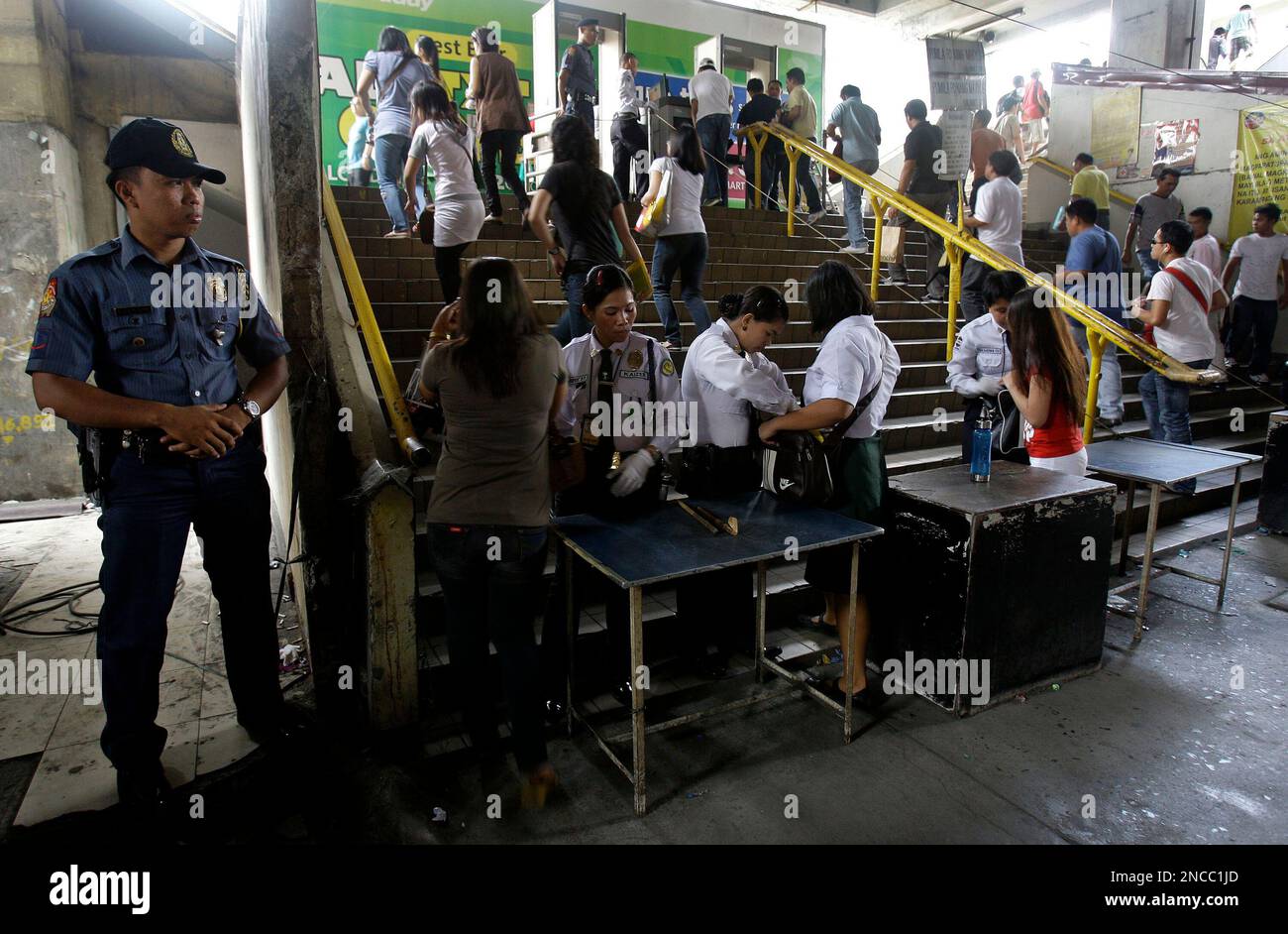 A Filipino policeman stands guard as security guards inspect the bags ...