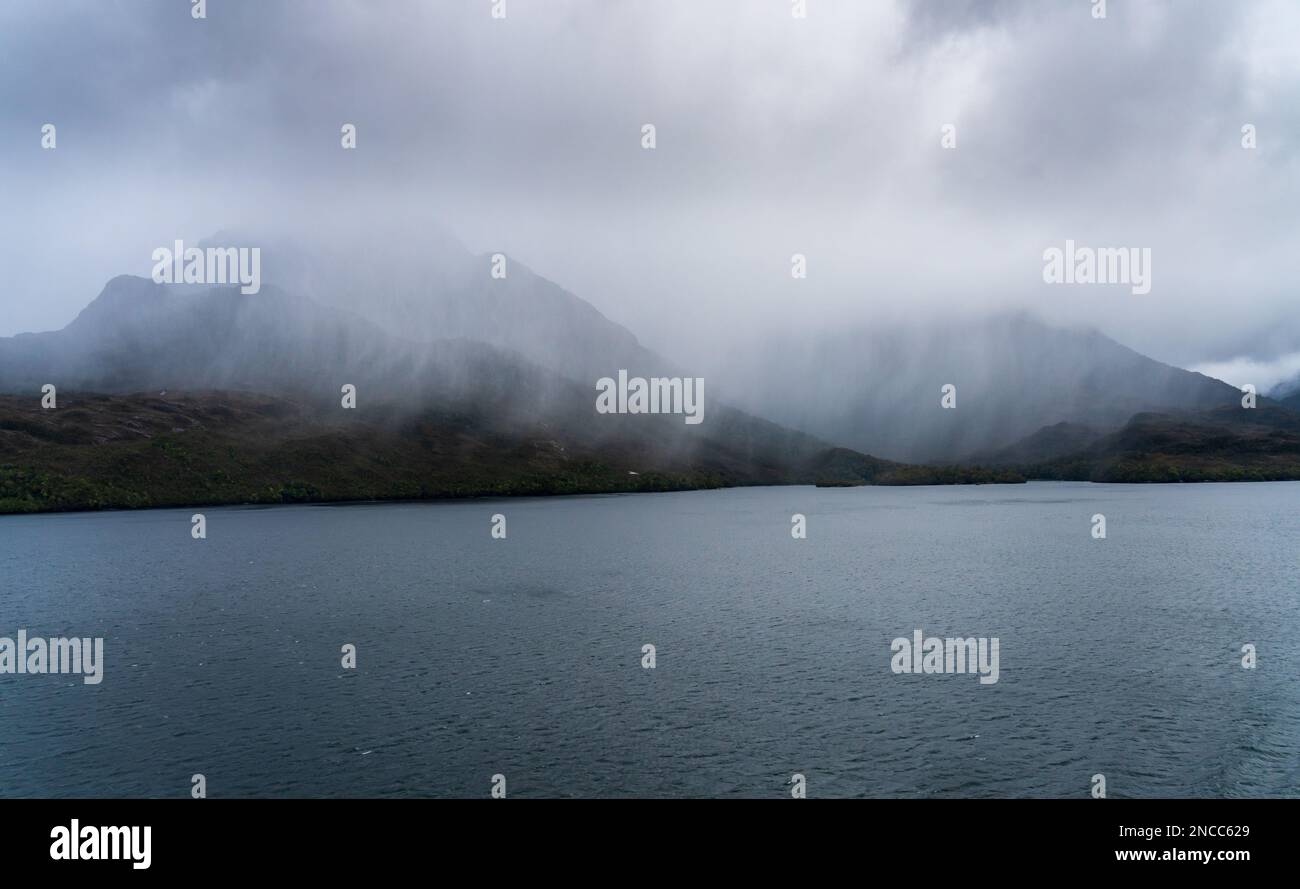 Rain over the mountains as cruise ship with swimming pool sails through ...