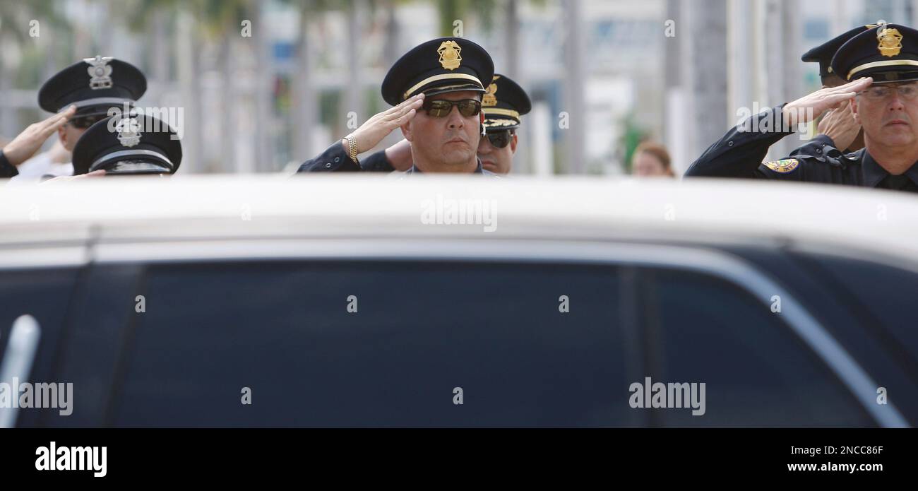 Police officers salute the procession bringing the bodies of two Miami ...