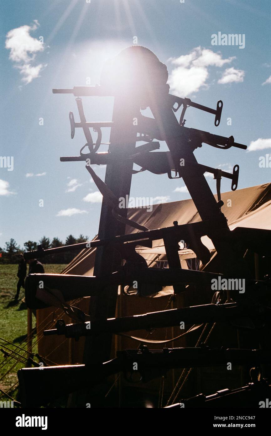 A rack of WWII vintage rifles with a helmet on top with sun flares ...