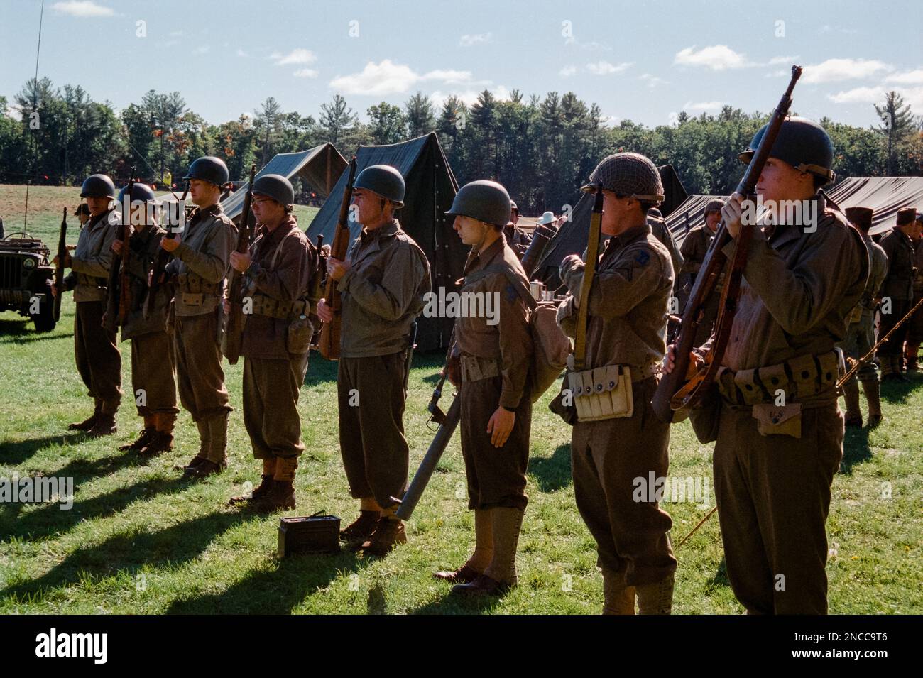 WWII troops stand at attention for inspection at a tent camp during a ...