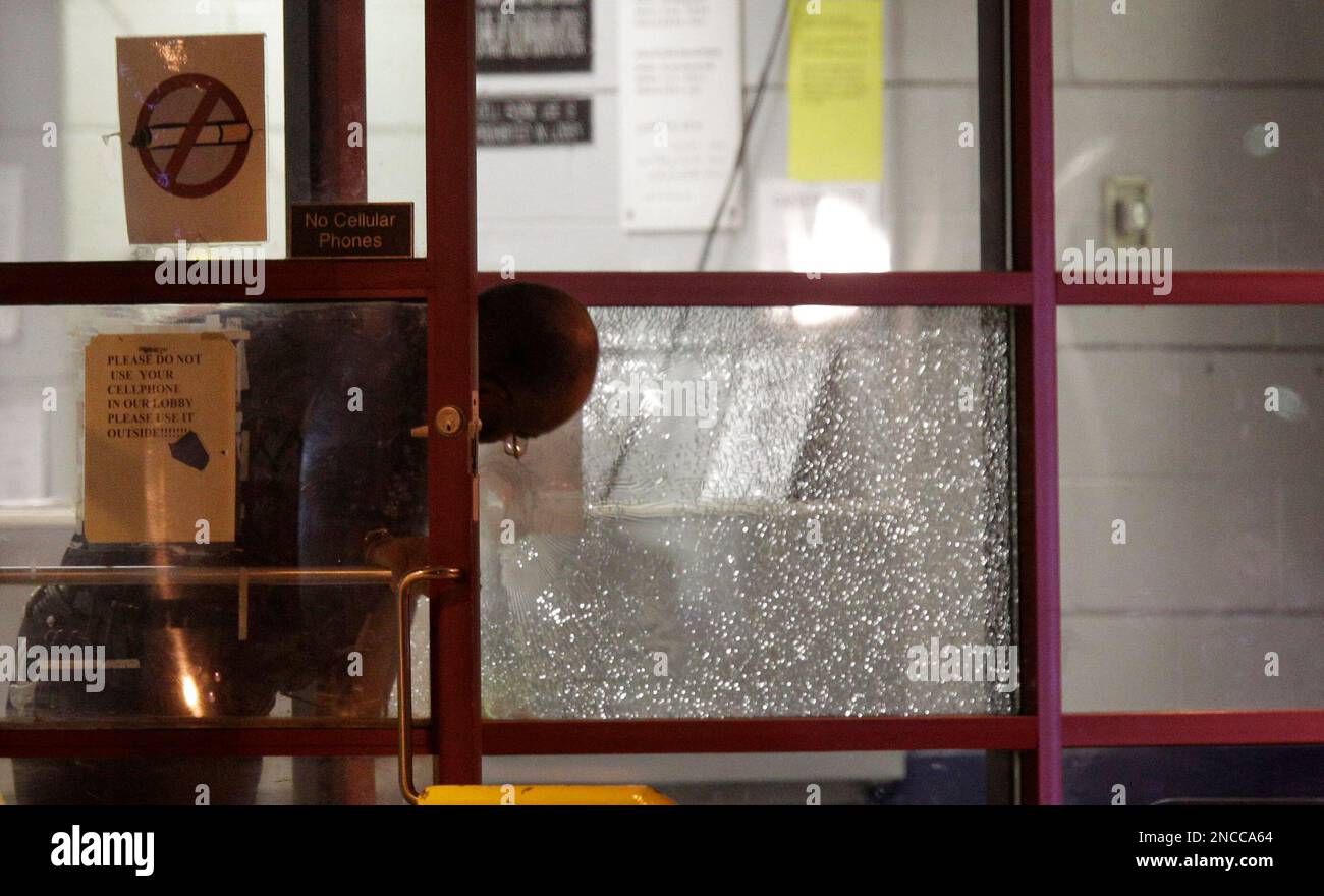 A Detroit police officer looks over one of the plate glass windows that ...