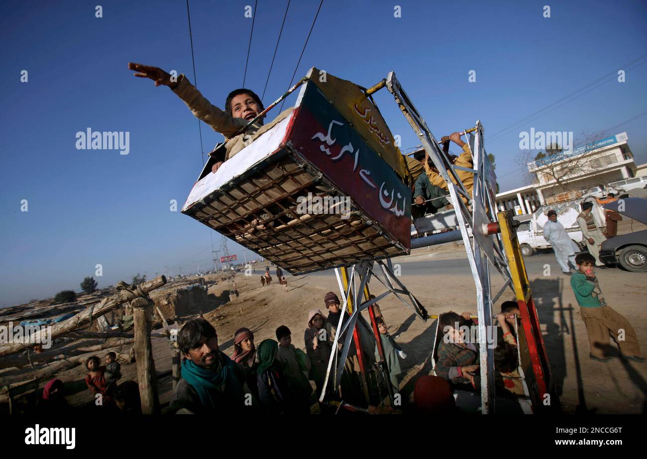 A Pakistani boy enjoys a amusement ride on a wheel, in a slum area on ...