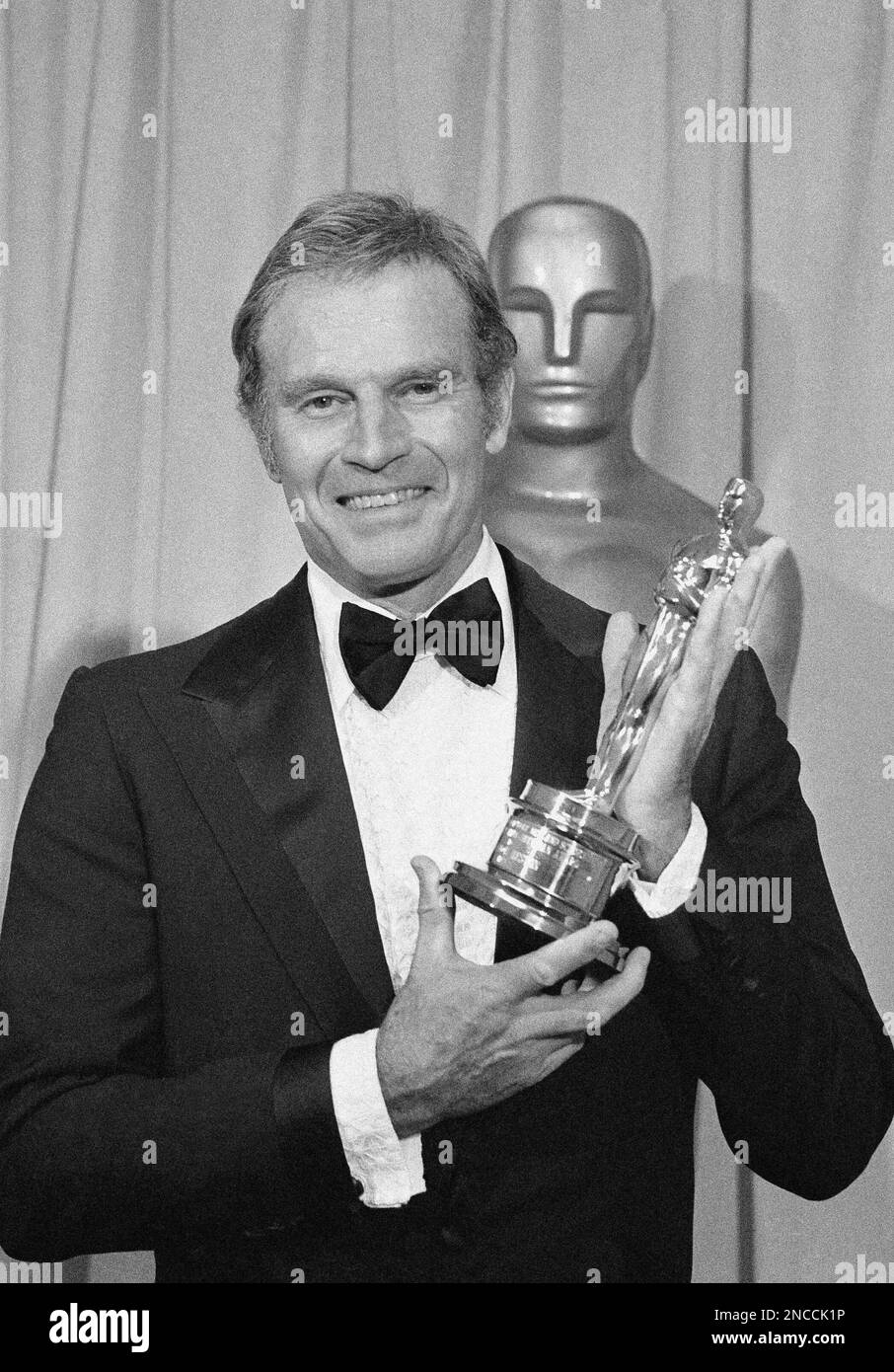 Charlton Heston holds up the Oscar presented to him as the Gene ...