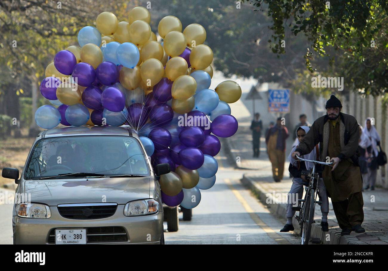 A Pakistani drives a car loaded with balloons along a street in ...