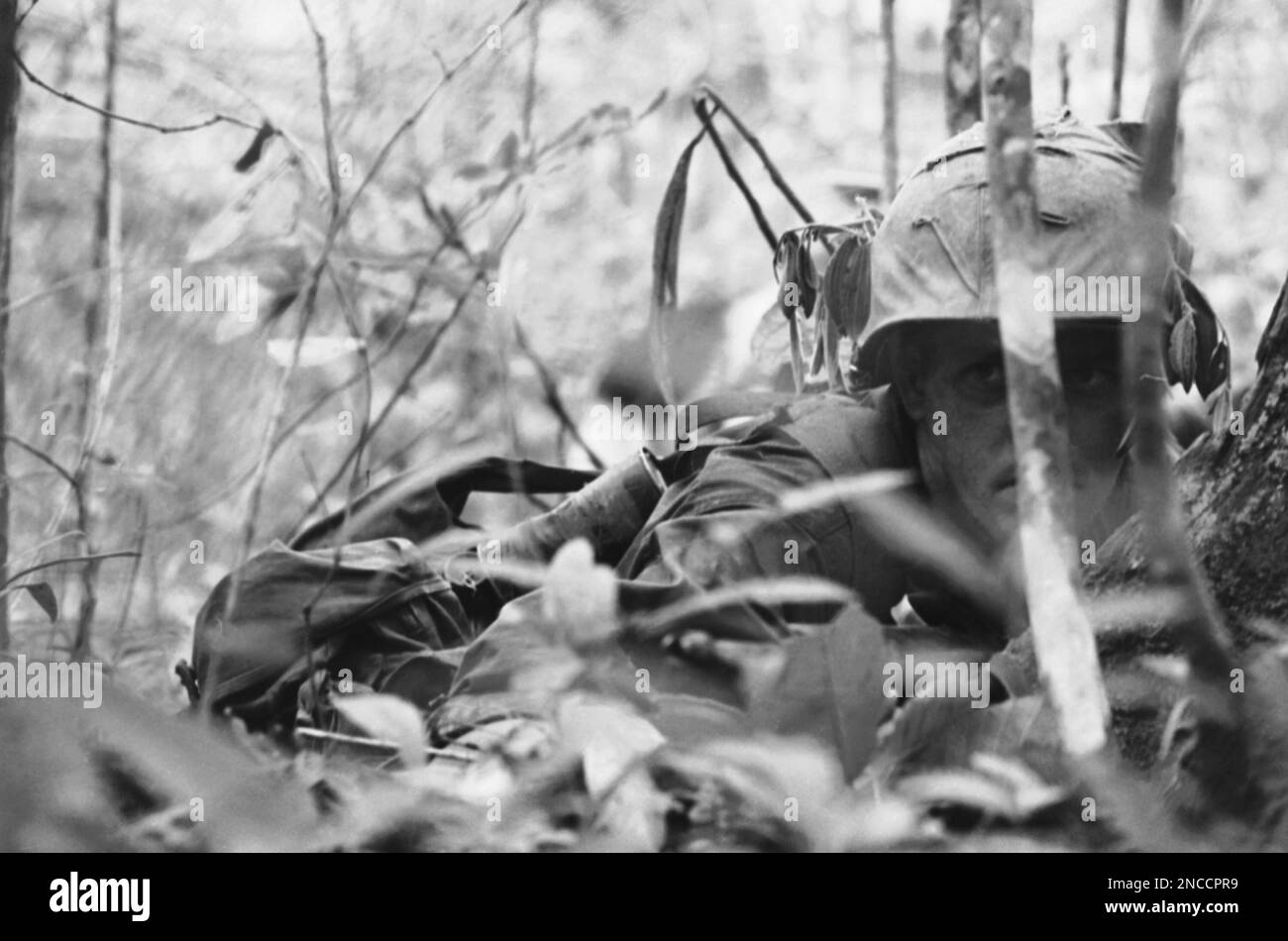An American infantryman presses close to the ground as he scans the ...