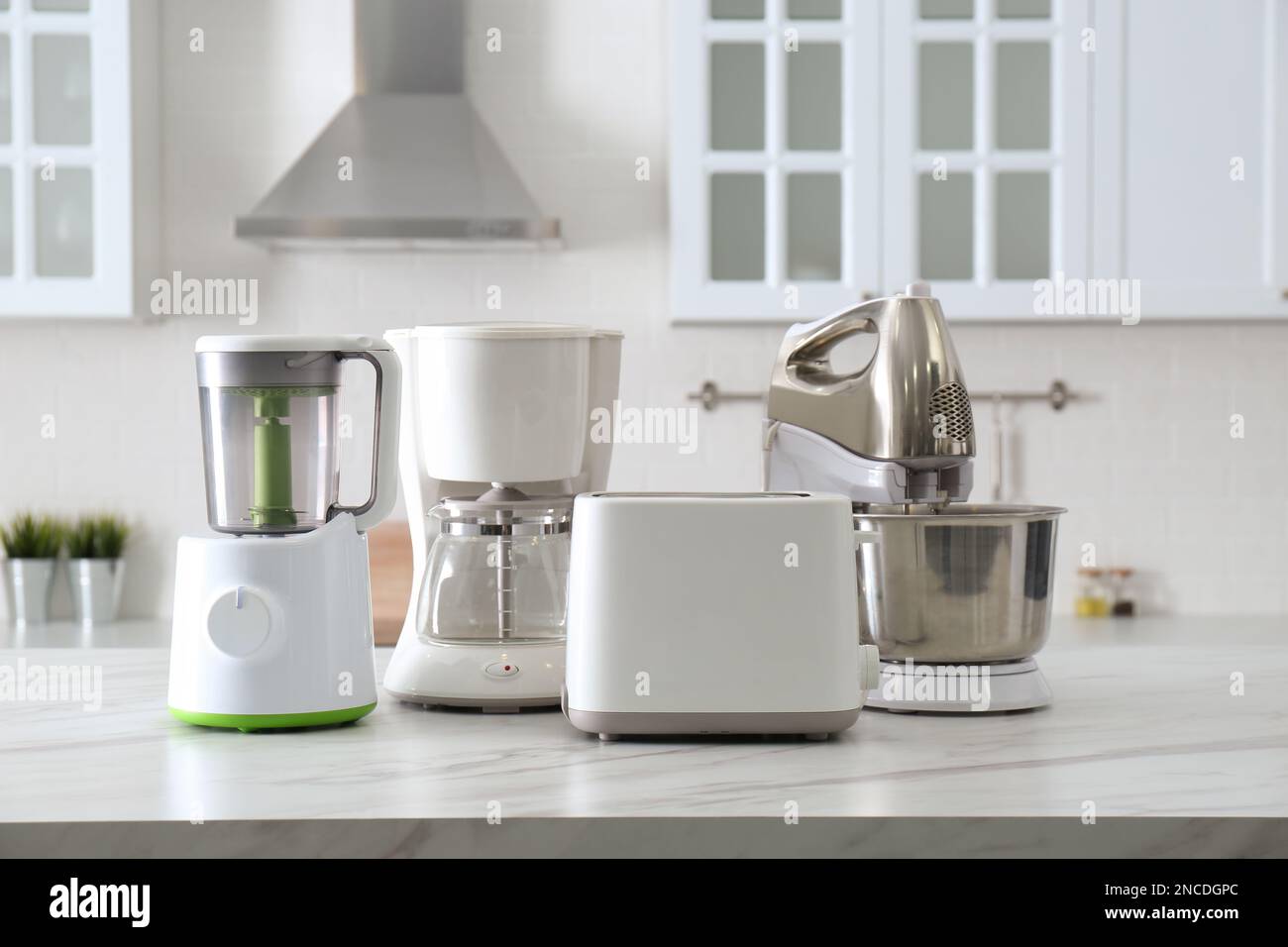 Modern toaster and other home appliances on white marble table in ...