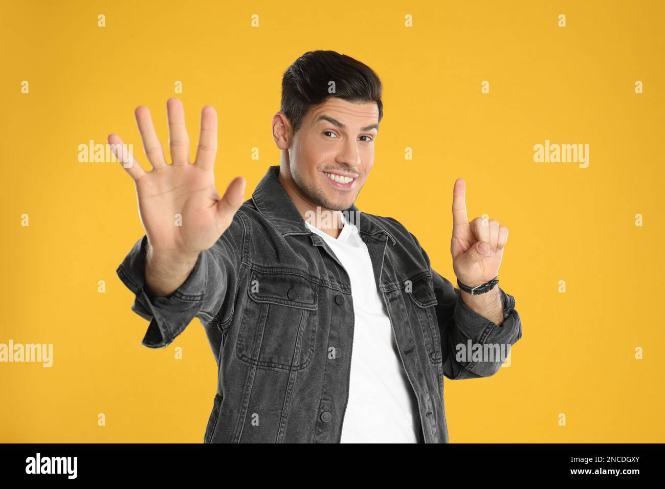 Man showing number six with his hands on yellow background Stock Photo ...