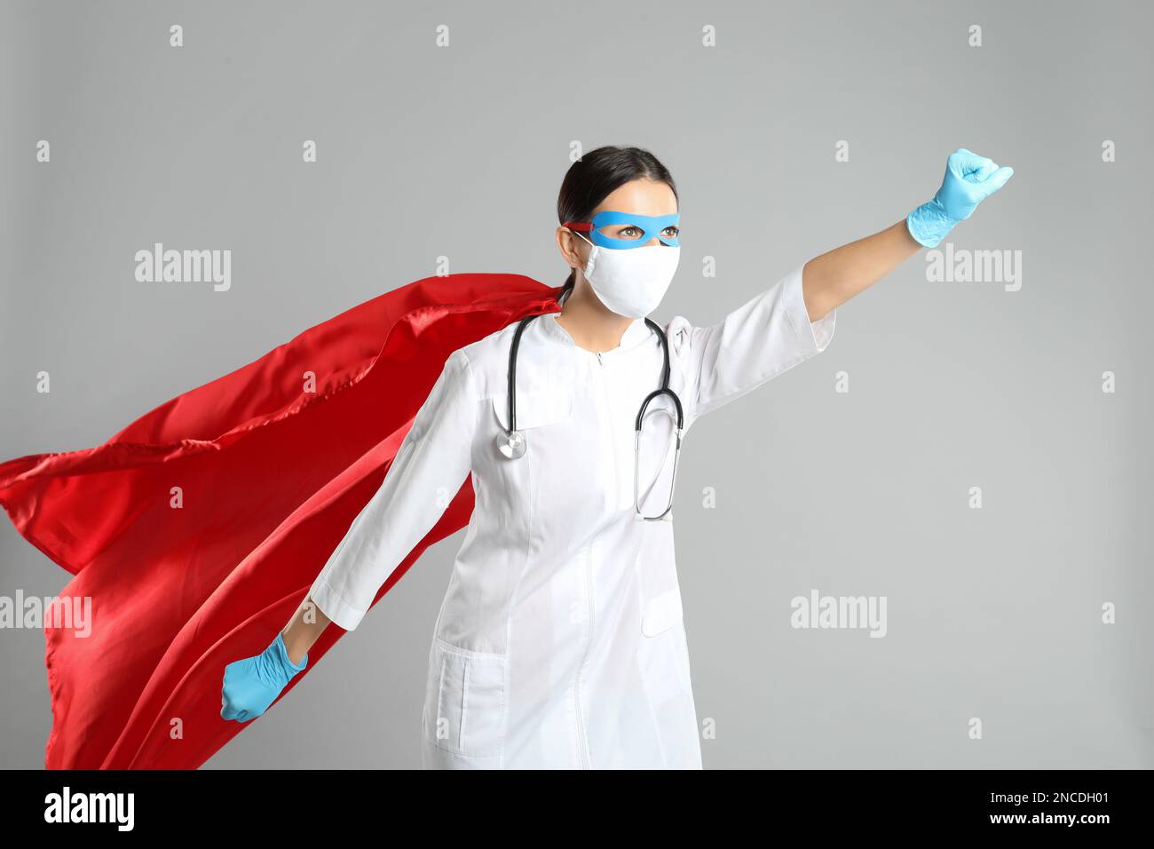Doctor dressed as superhero posing on light grey background. Concept of ...