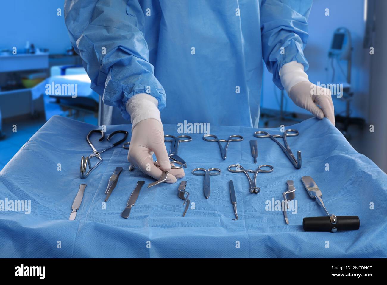 Nurse near table with different surgical instruments in operating room ...