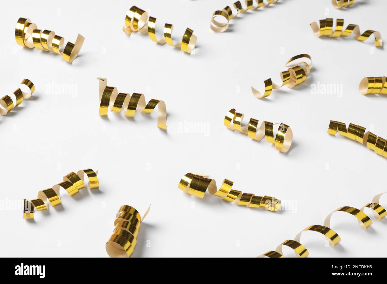 Shiny golden serpentine streamers on white background Stock Photo - Alamy