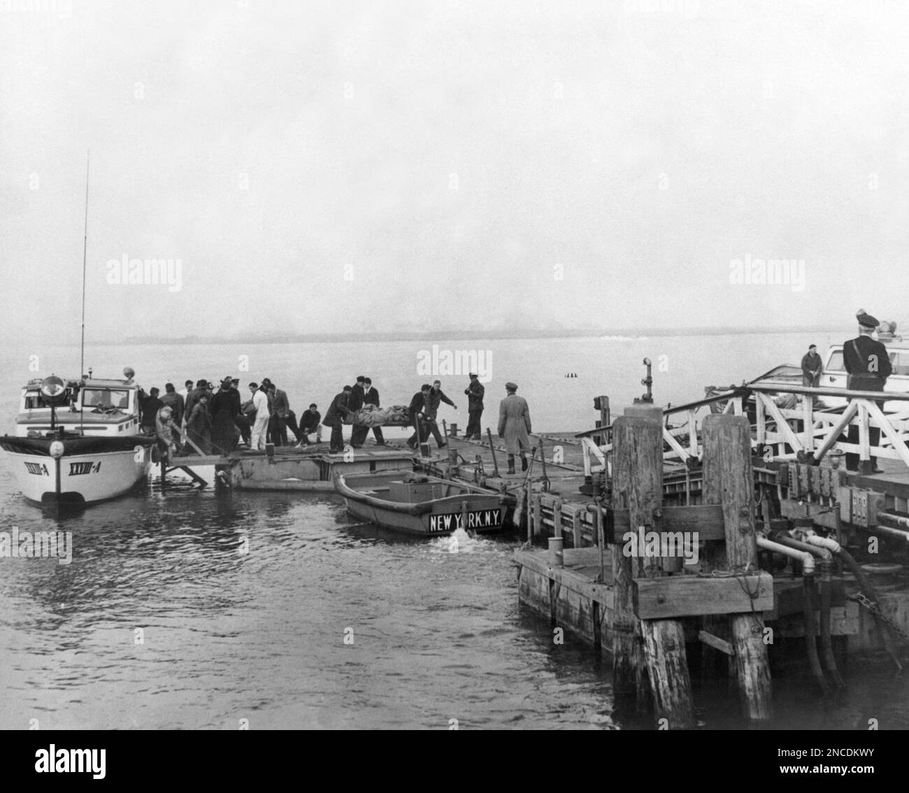 Survivors of the crash of a B-29 Super fortress are carried ashore from ...