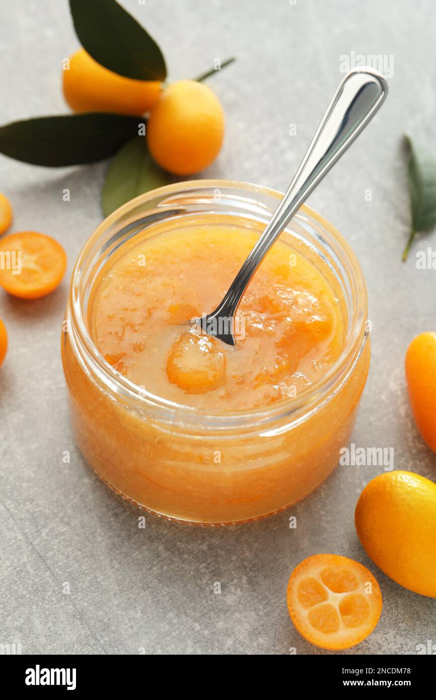 Delicious kumquat jam and fresh fruits on light grey table Stock Photo ...