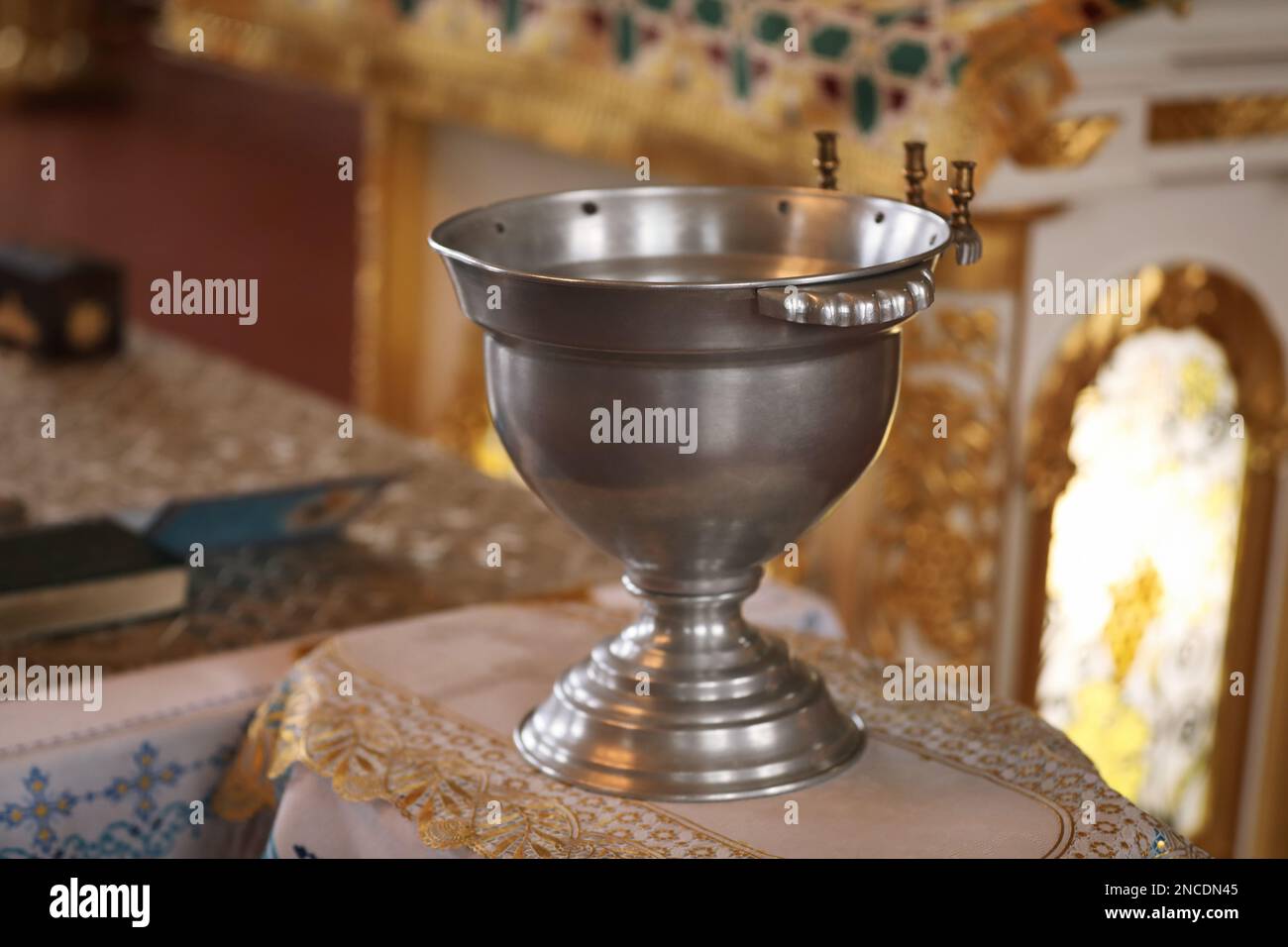 Silver vessel with holy water on stand in church. Baptism ceremony Stock Photo - Alamy