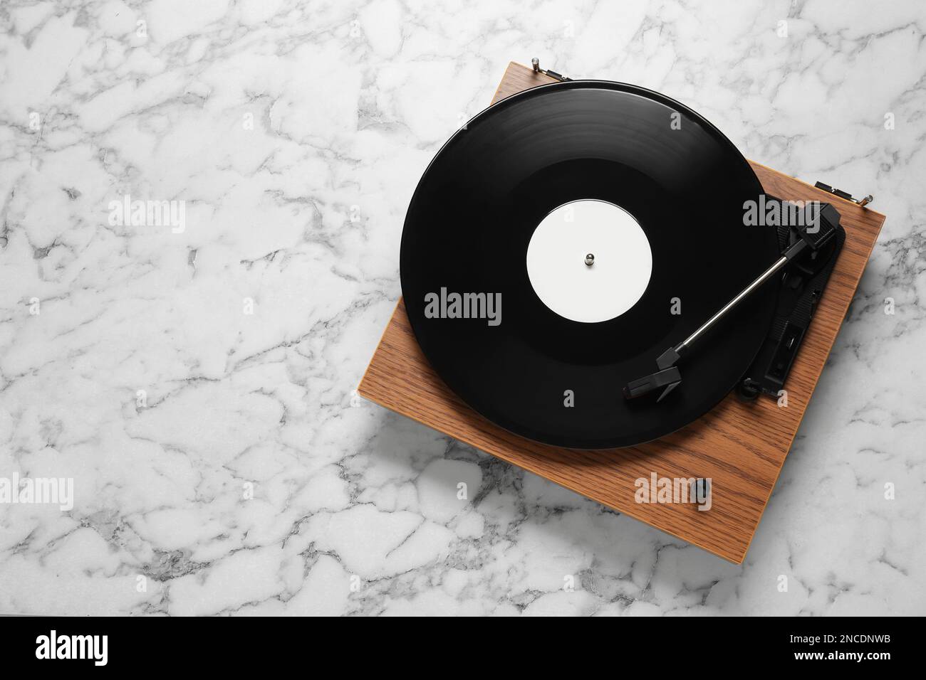 Turntable with vinyl record on white marble background, top view. Space ...