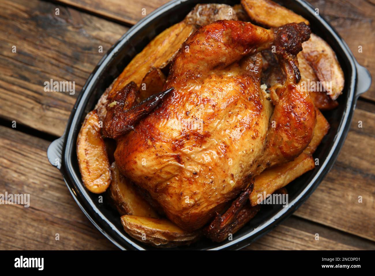 Delicious grilled whole chicken with potato in plastic container on ...