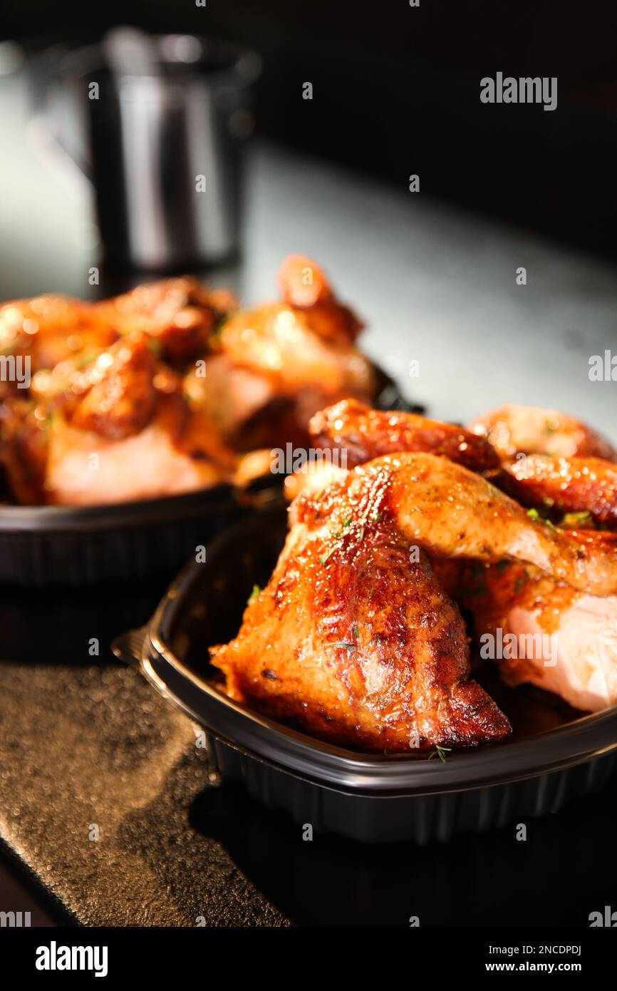 Cooked pieces of grilled chicken in plastic containers on bar counter ...