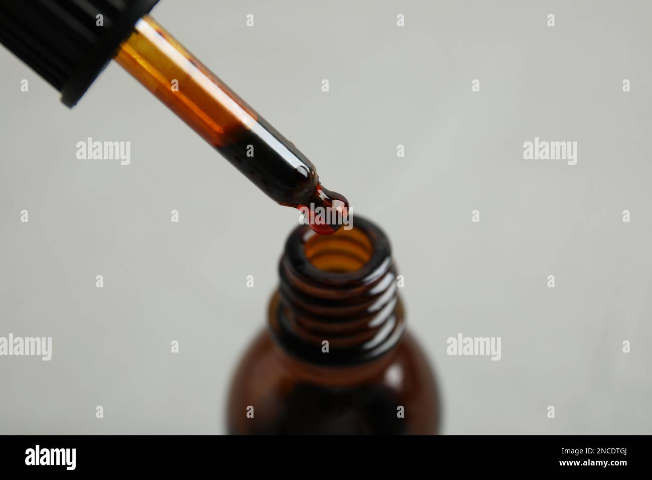 Dripping medical iodine from pipette into glass bottle on grey ...