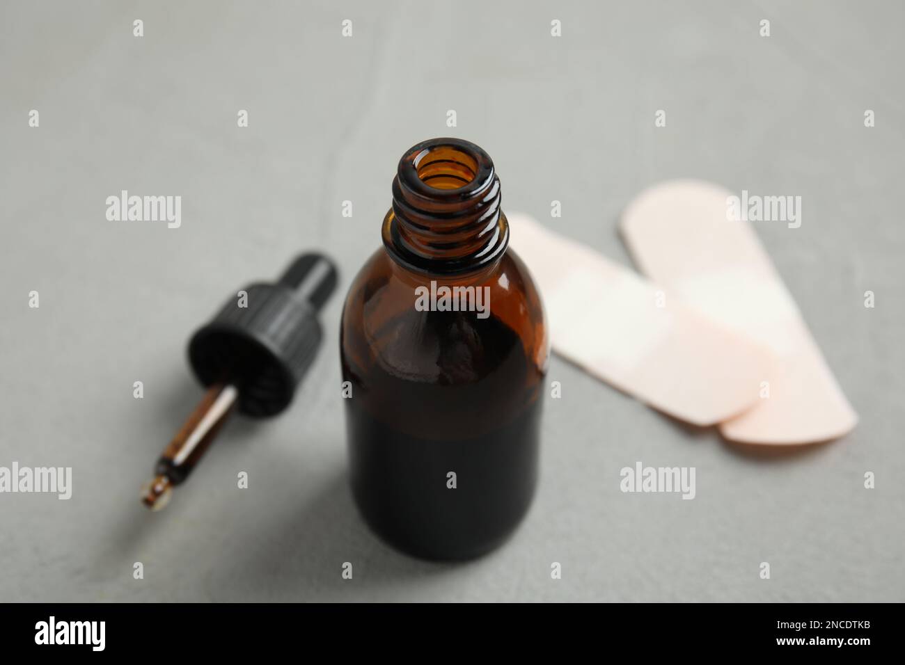 Bottle of medical iodine, dropper and sticking plasters on grey table ...