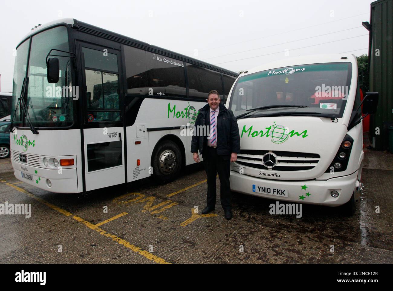 Adrian Morton, the owner of Mortons Travel, poses by two of his coaches ...