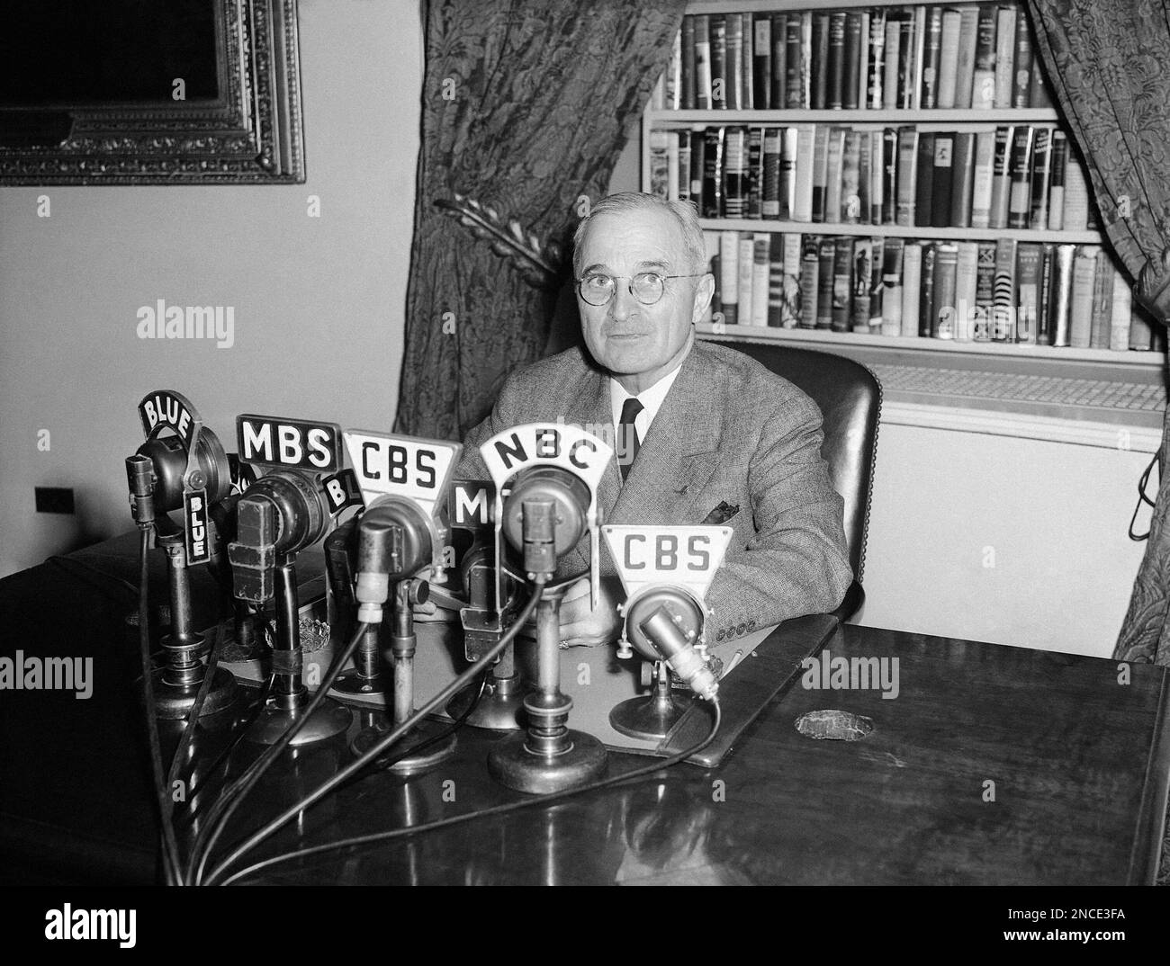 President Harry S. Truman talks in front of microphones over which he ...