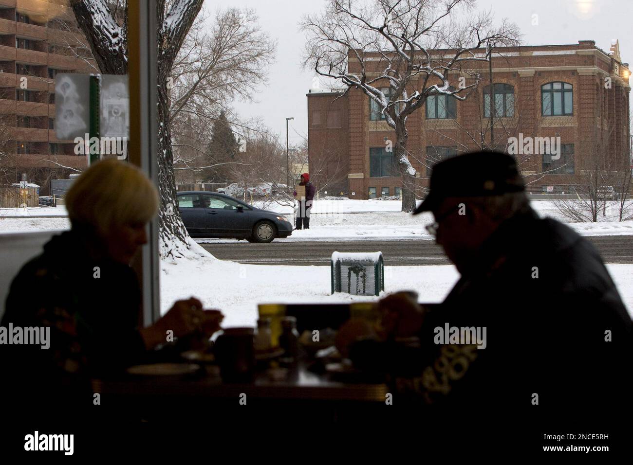 A homeless man stands on the side of a road in the cold snowie weather ...