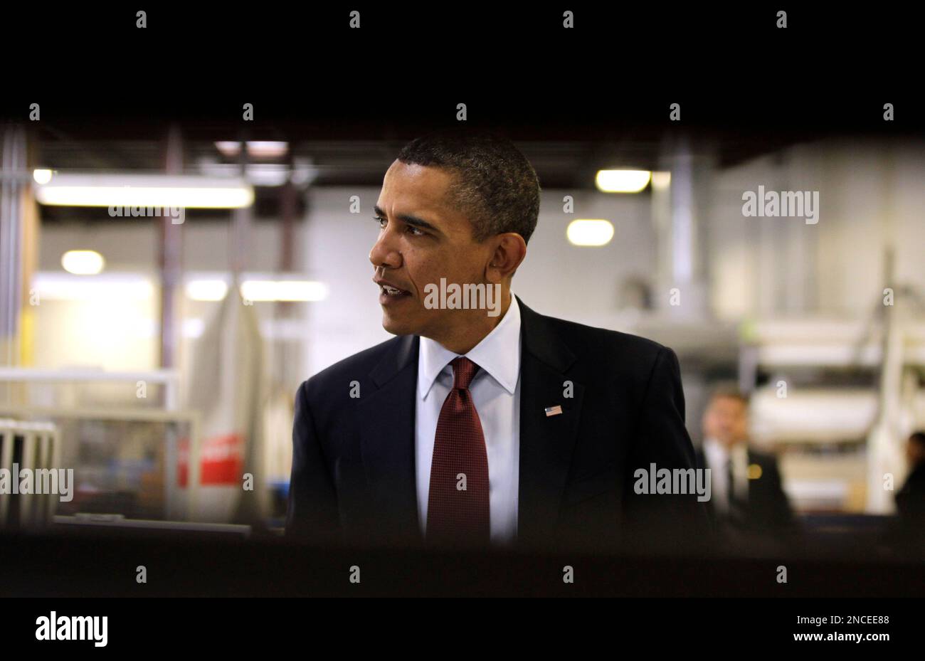 President Barack Obama is seen from behind pallets of vinyl window ...