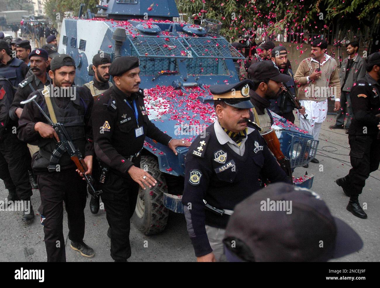Pakistani police officers escort an armoured car carrying Mumtaz Qadri ...