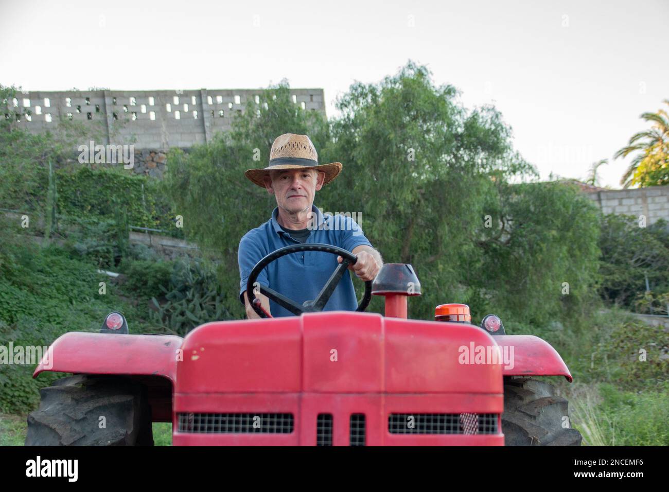 Frontal shot of a Caucasian farmer at the wheel of his farm tractor ...