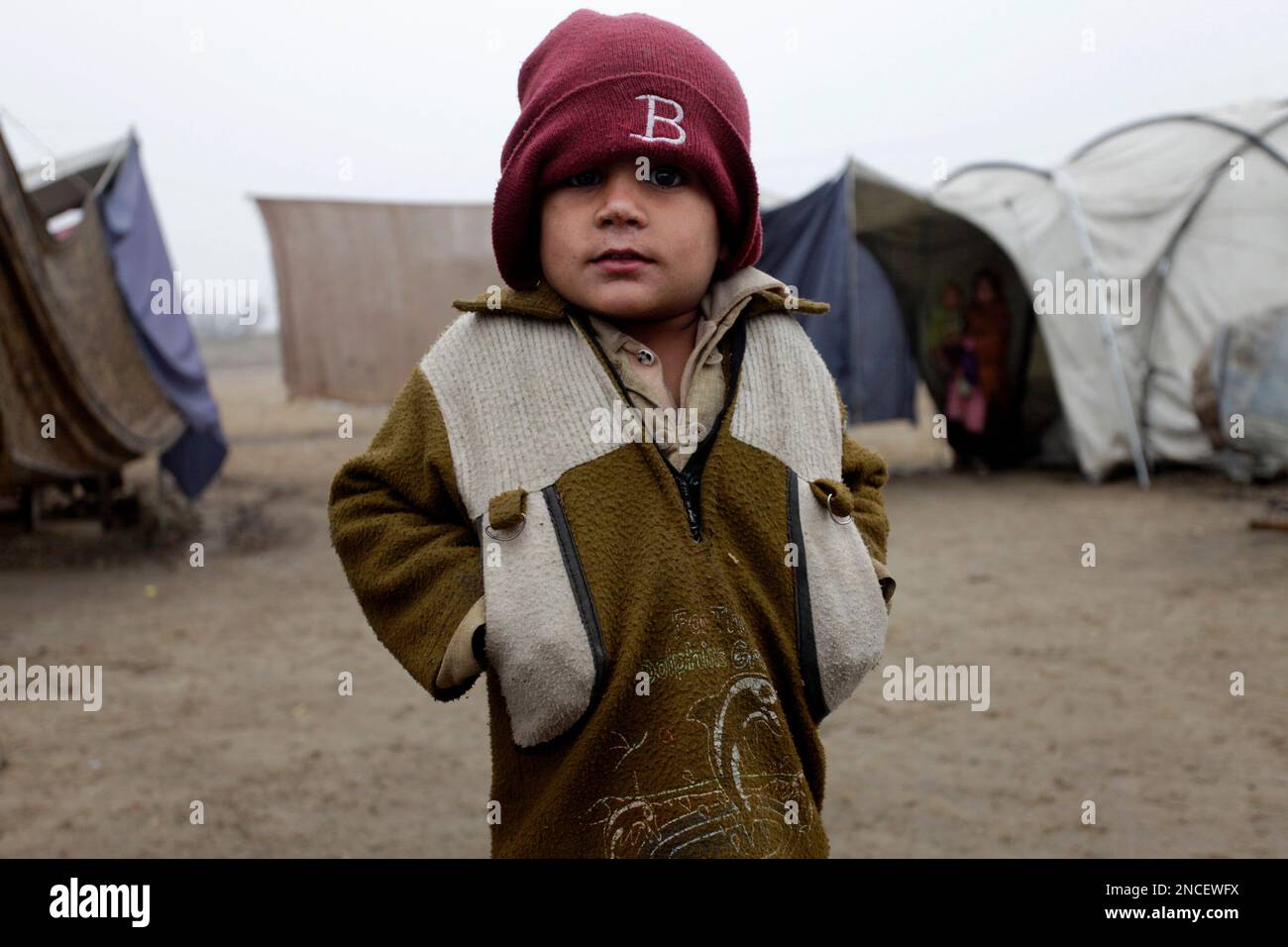 A Pakistani child poses for a photograph outside his tent in a slum in ...