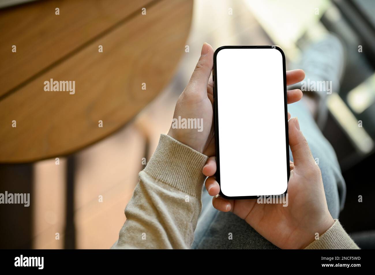 Top view image of a woman's hands holding a smartphone white screen ...