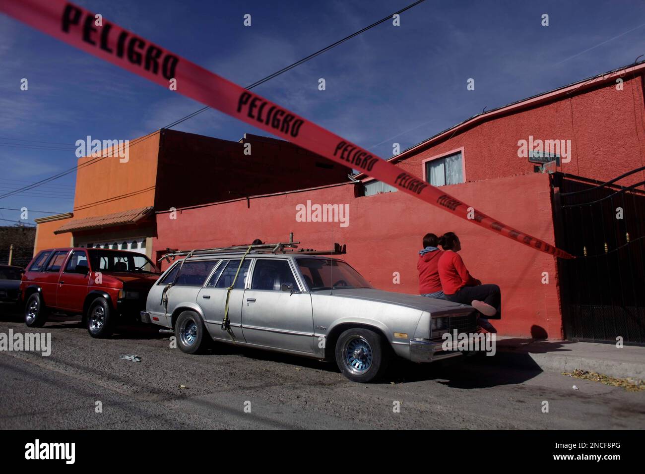 In this photo taken Dec. 14, 2010, two women watch police investigate ...