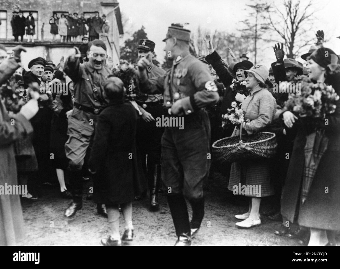 Adolf Hitler, left, receiving floral tributes upon his arrival for a ...