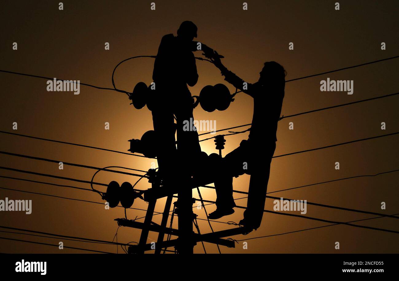Indian linemen are silhouetted as they repair high tension wires on the ...