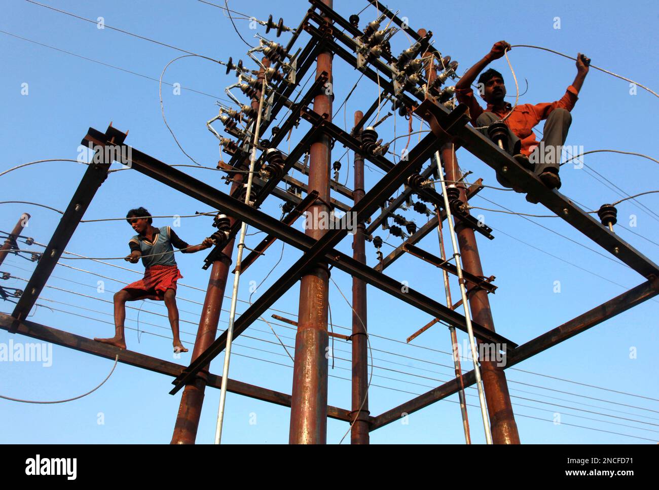 Indian linemen repair high tension wires on the banks of the Ganges ...