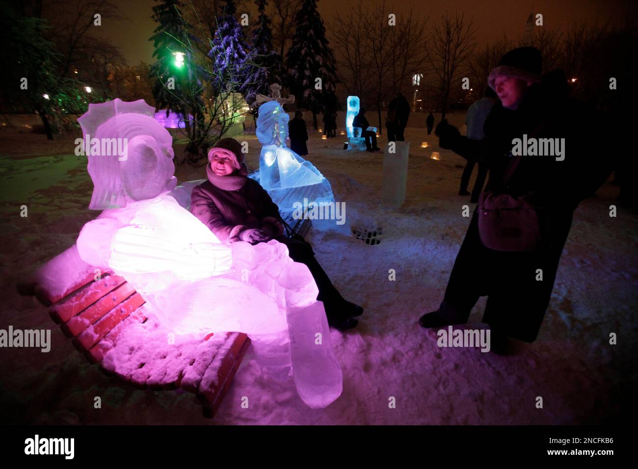 Visitors take photos of each other as they pose sitting next to ice ...