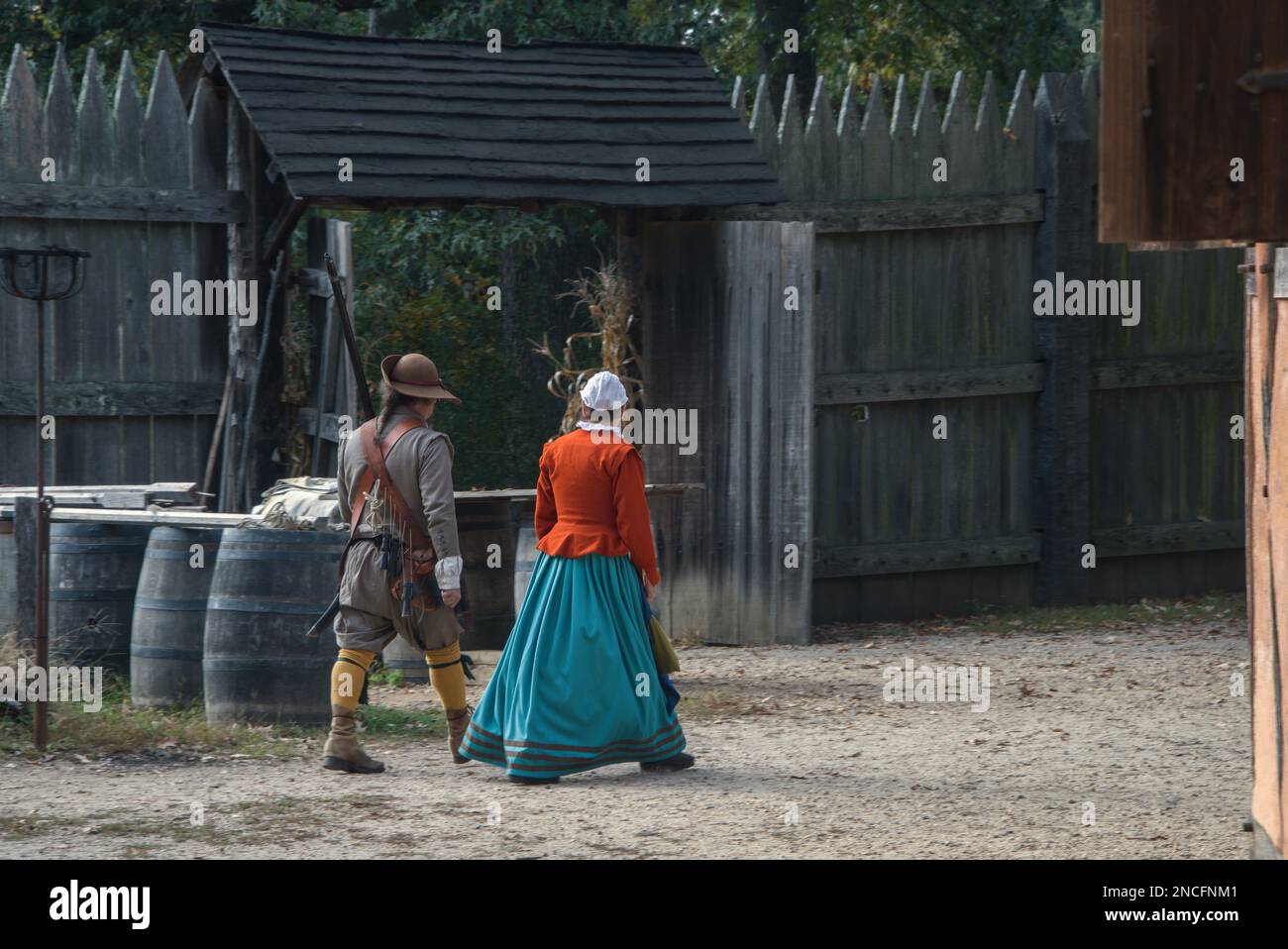 A man and a woman in period dress, walking across the re-creation of ...