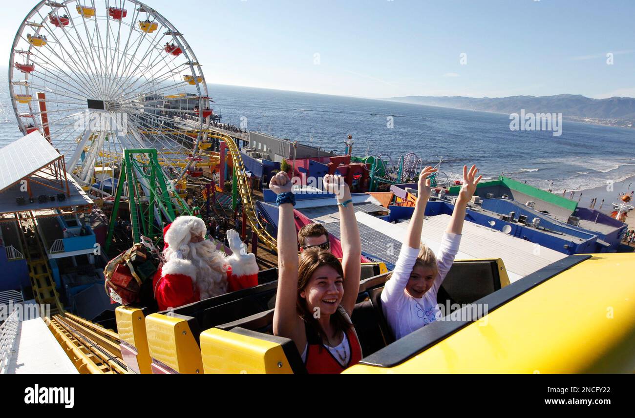 Visitors ride along with life-sized figure of Santa Claus on the roller ...