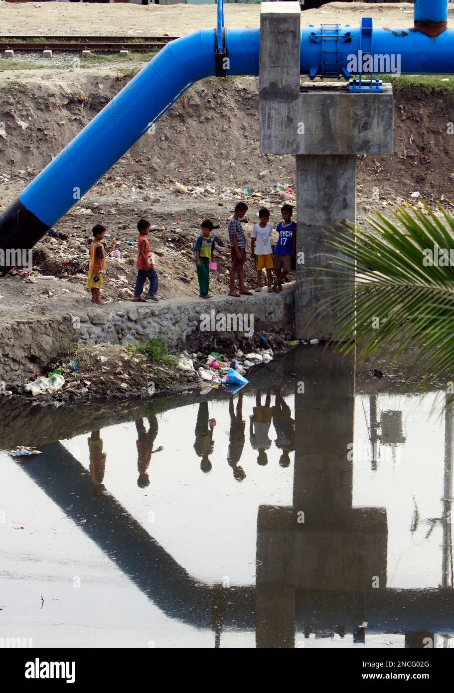 A group of children are reflected on the water as they play under a ...