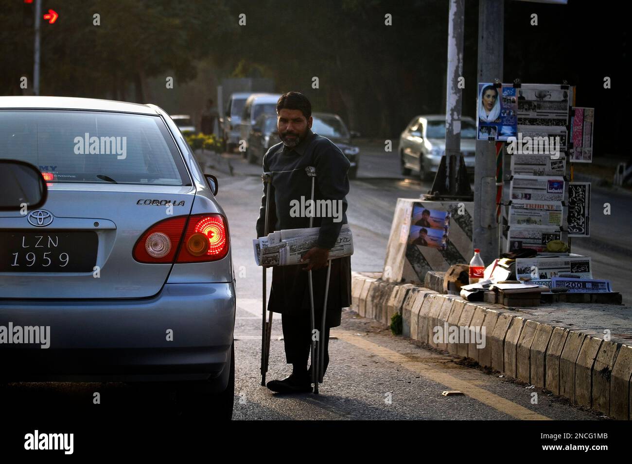 A physically-challenged Pakistani sells newspape at an intersection in ...