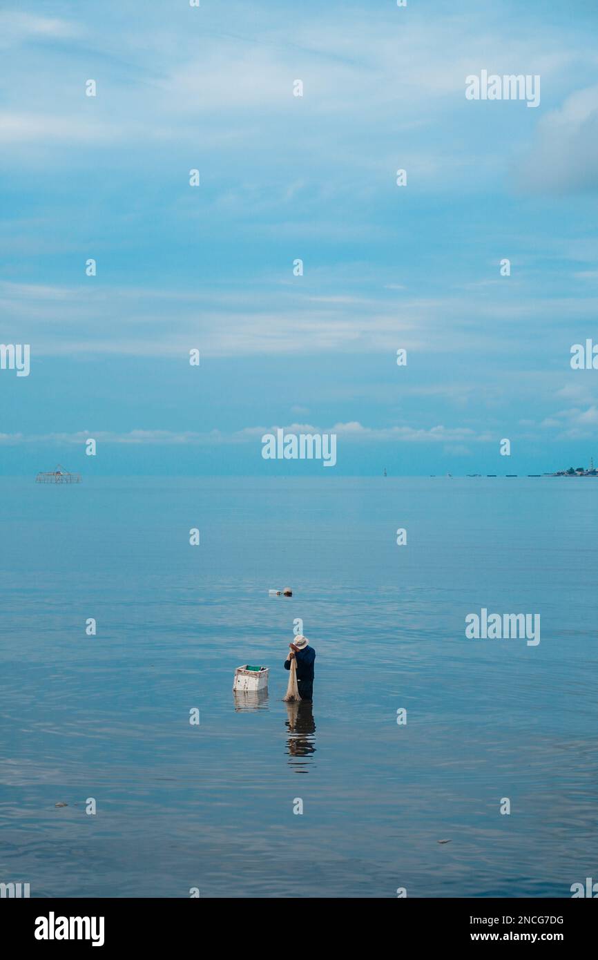 Old fishermen looking for fish on the beach with nets and cork boxes ...