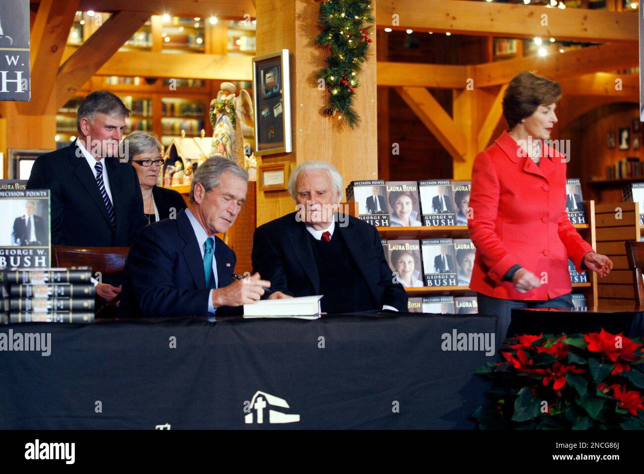 Former President George W. Bush, center left, autographs a book for ...
